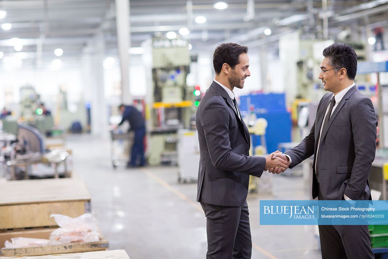 Business people shaking hands in the factory-High-res stock photo for download