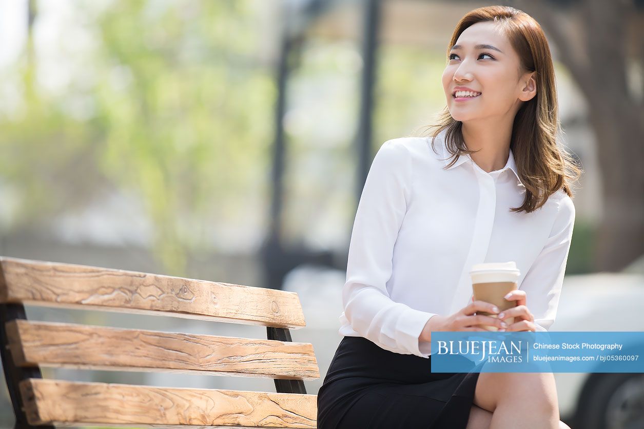 Cheerful young Chinese businesswoman drinking coffee-High-res stock photo for download