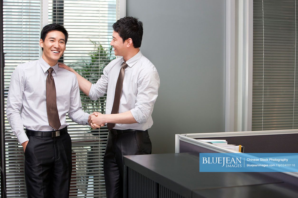 Young Chinese businessman congratulating other young businessman-High ...