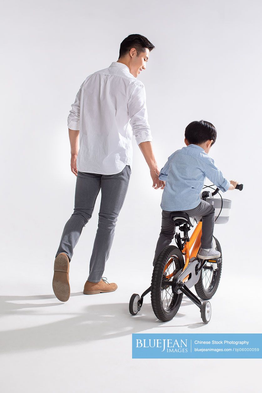Chinese father teaching son to ride bike-High-res stock photo for download
