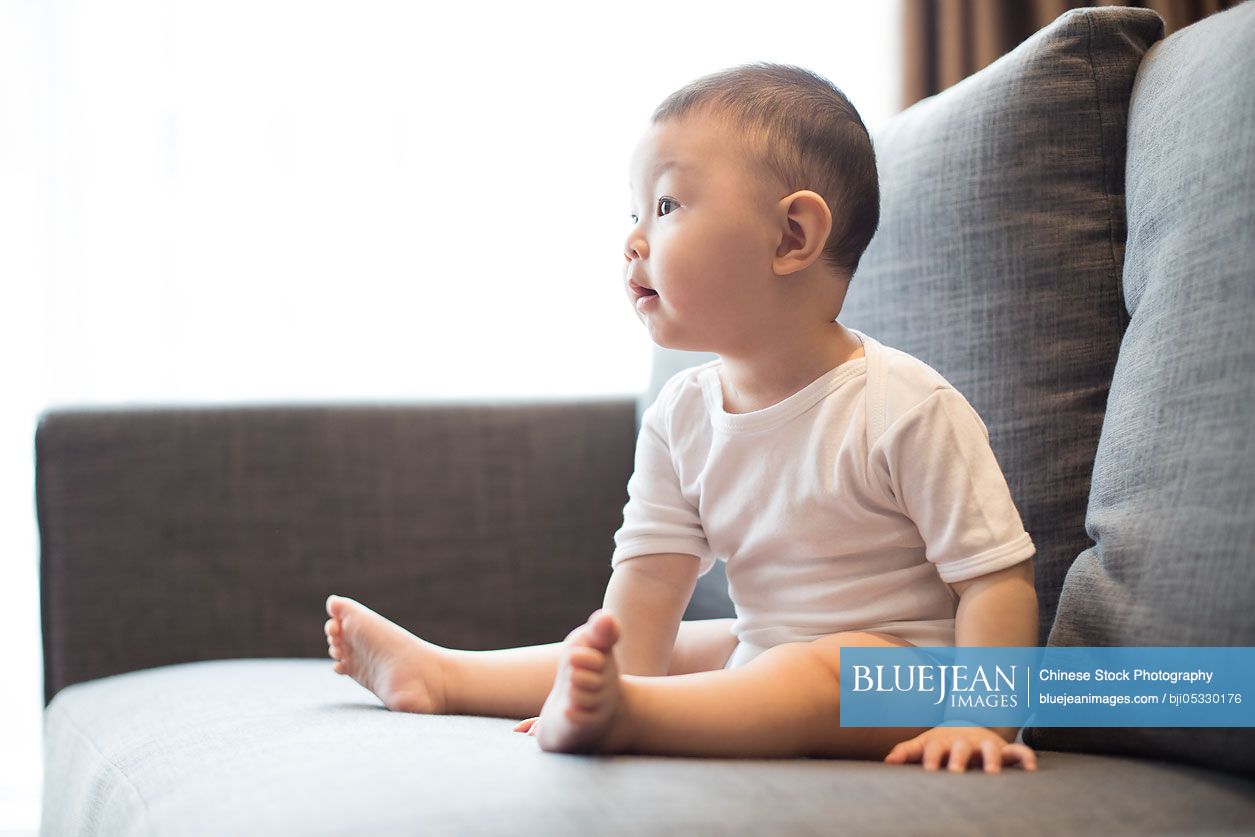 Cute Chinese baby boy sitting on sofa-High-res stock photo for download