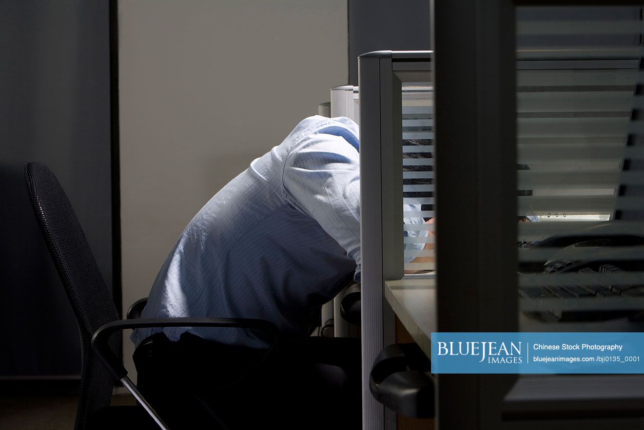 Young Chinese man lays head on desk in cubicle-High-res stock photo for ...