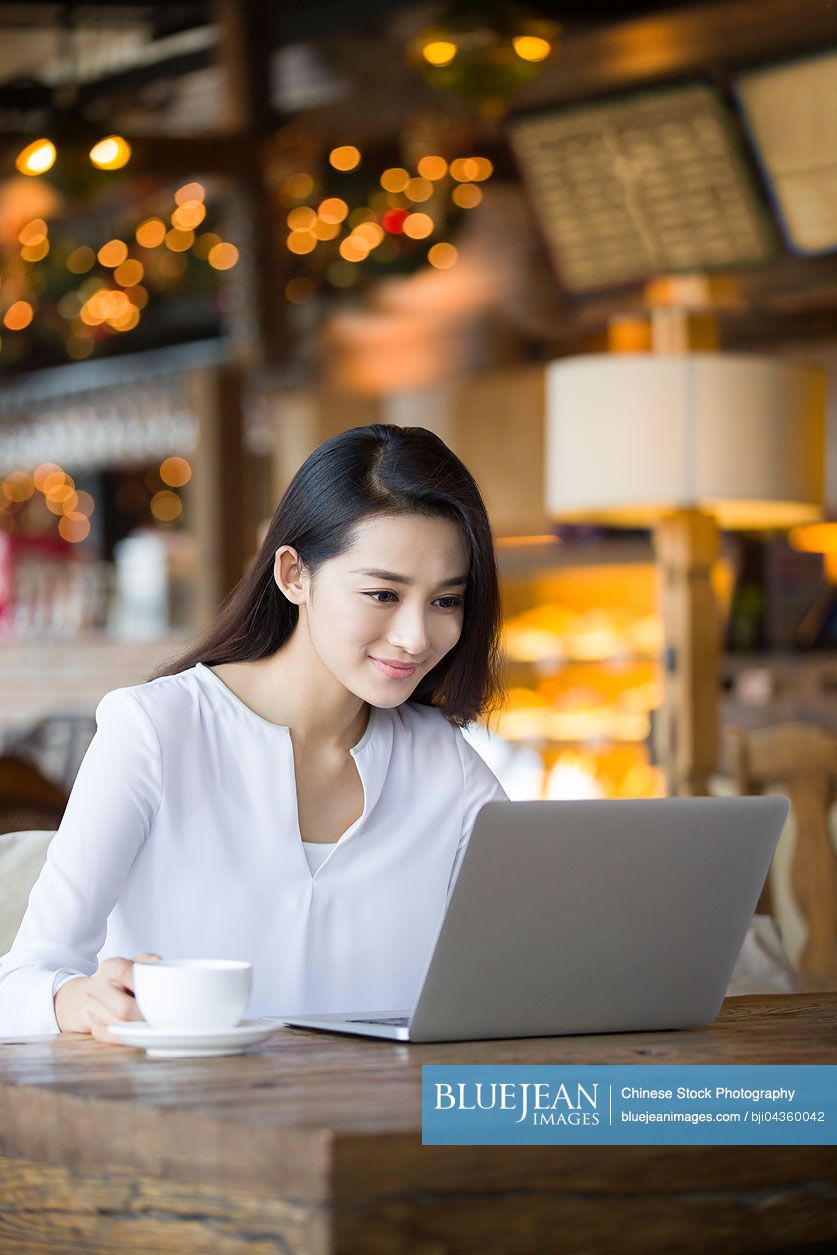 Young Chinese woman using laptop in cafe-High-res stock photo for download