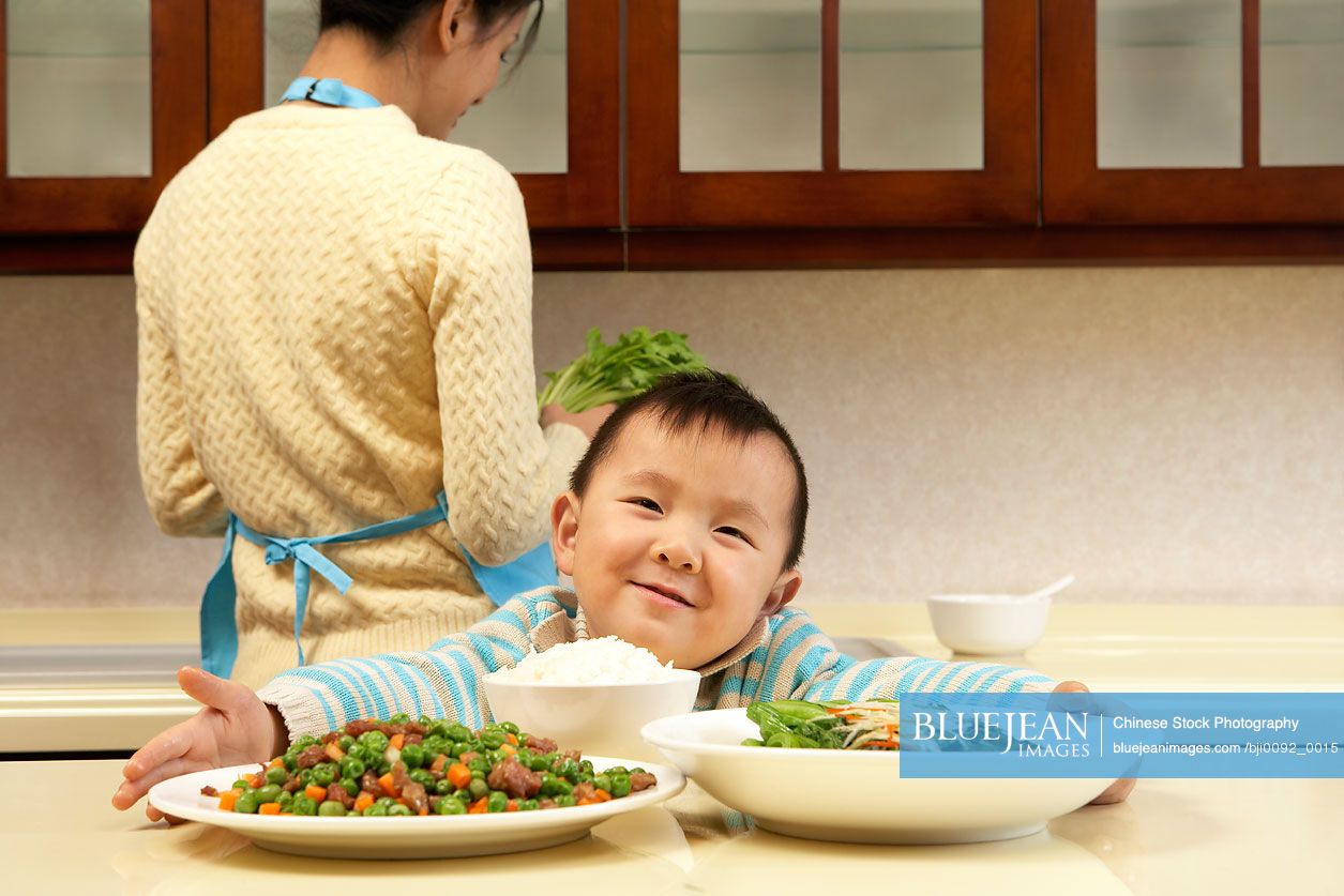 Young Chinese boy holding plates of food at the dinner table-High-res ...