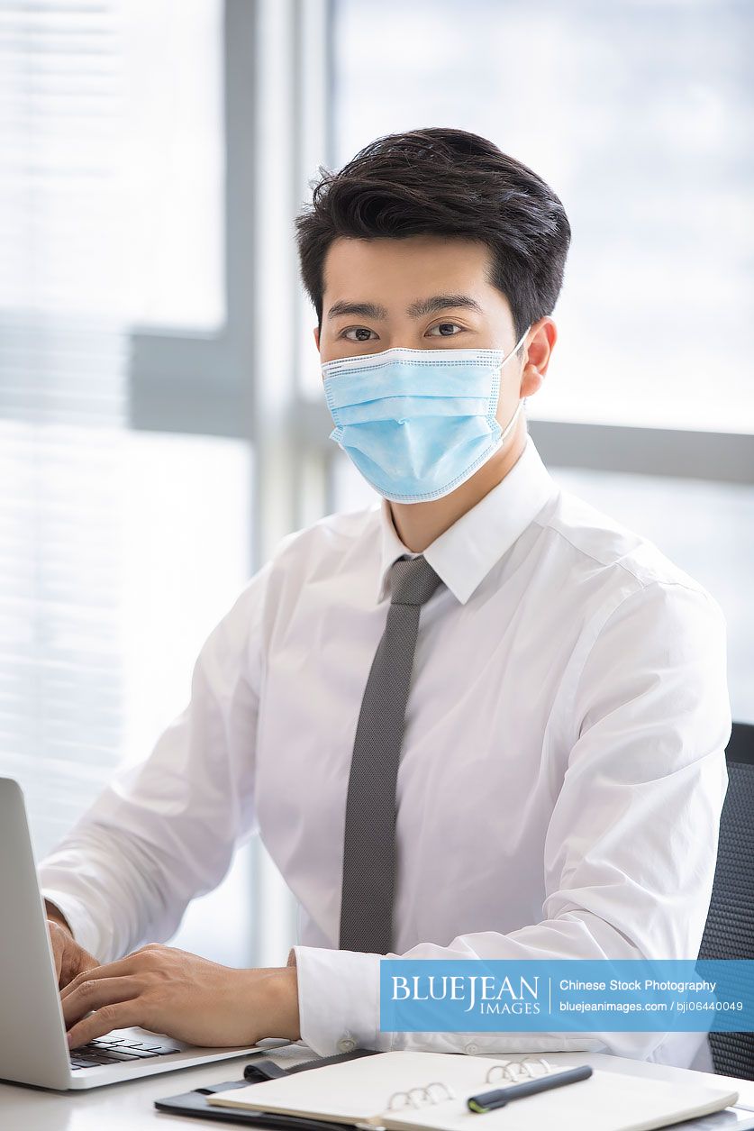 Young Chinese businessman wearing surgical mask in office-High-res ...
