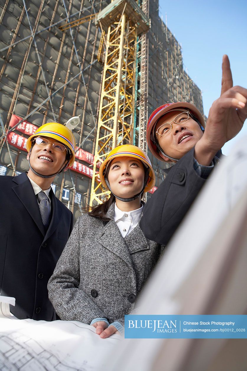 Chinese businesspeople in construction site wearing hard hats-High-res ...