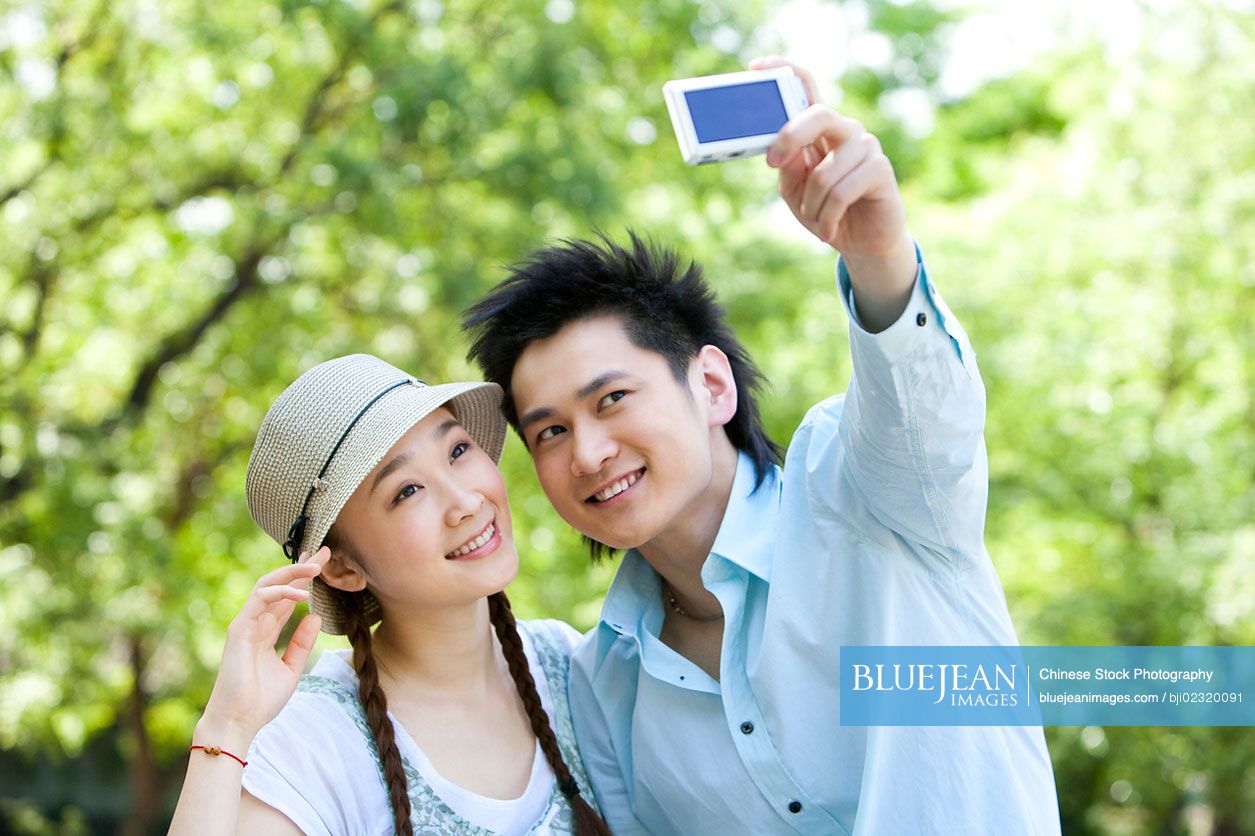 Happy young Chinese couple taking photos in the park-High-res stock photo for download
