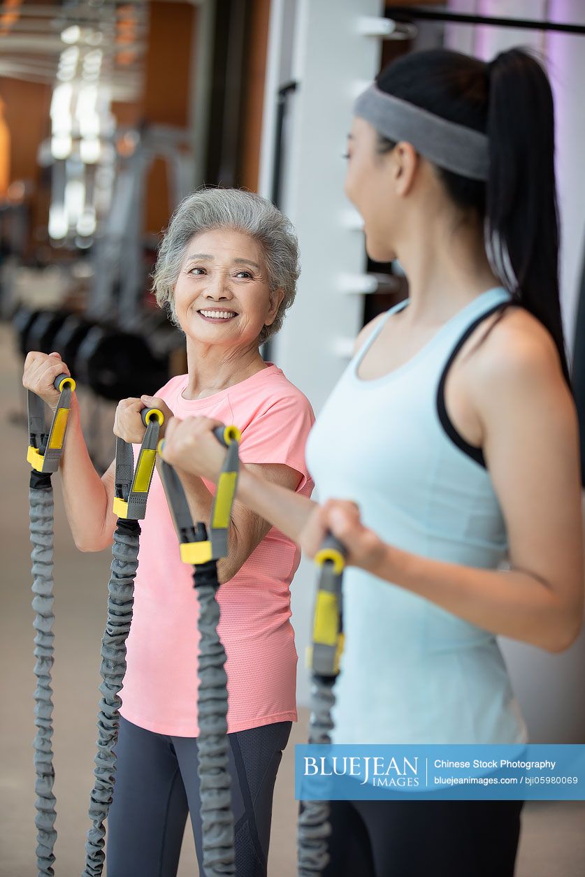 Senior Chinese woman working out with personal trainer at gym-High-res stock photo for download