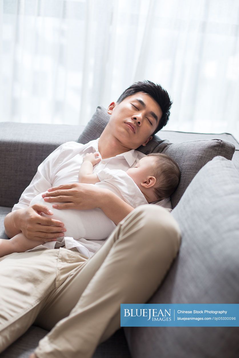 Young Chinese father and baby boy sleeping on sofa-High-res stock photo for download