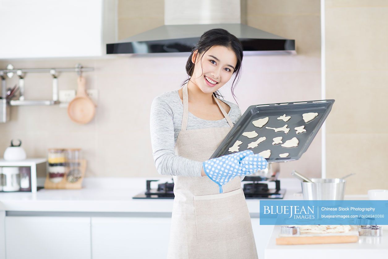Young Chinese woman making cookies in kitchen-High-res stock photo for download