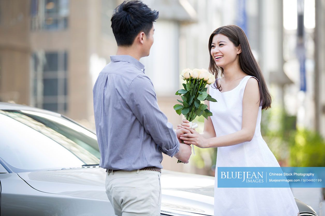 Young Chinese man giving flowers to girlfriend-High-res stock photo for ...