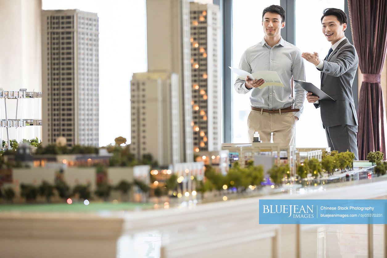 Chinese realtor showing architectural model to young man-High-res stock photo for download