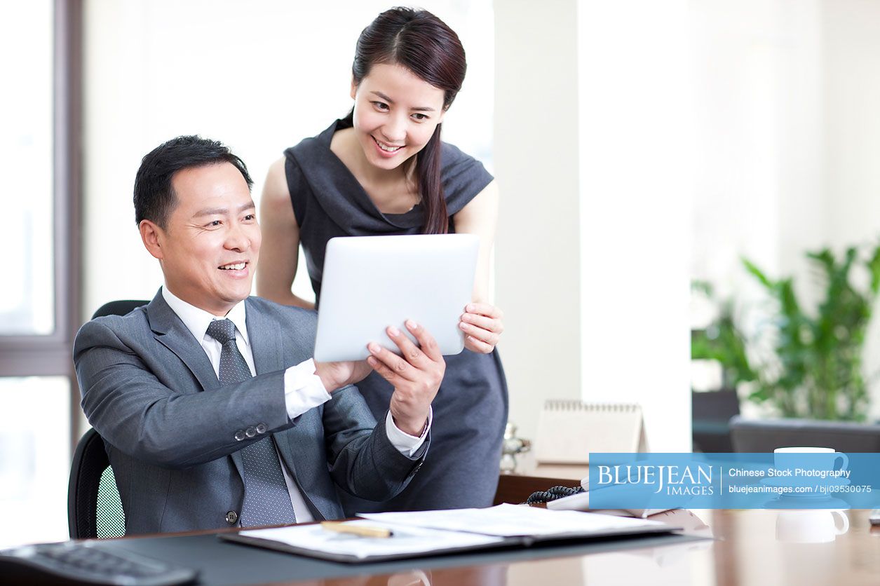 Happy Chinese business colleagues using digital tablet in office-High ...