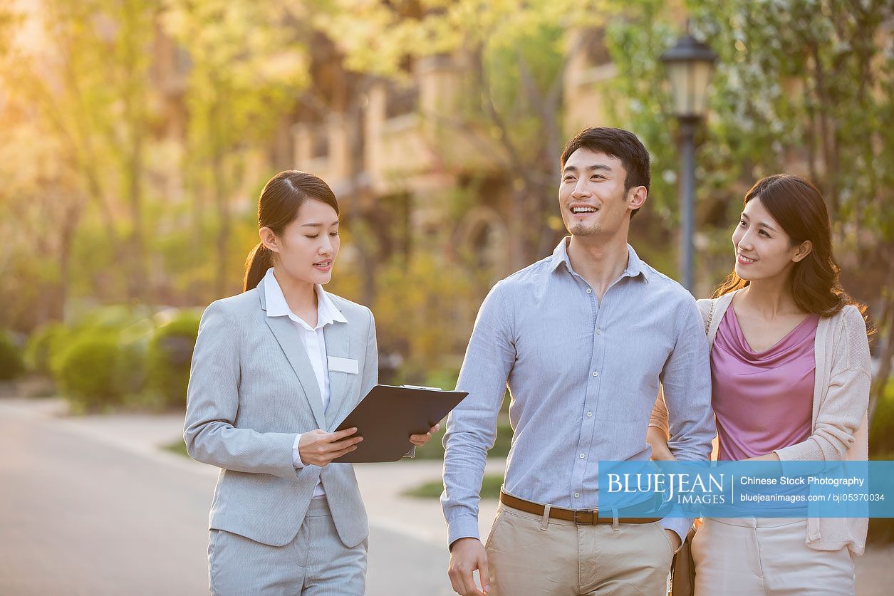 Happy young Chinese couple talking with realtor-High-res stock photo ...