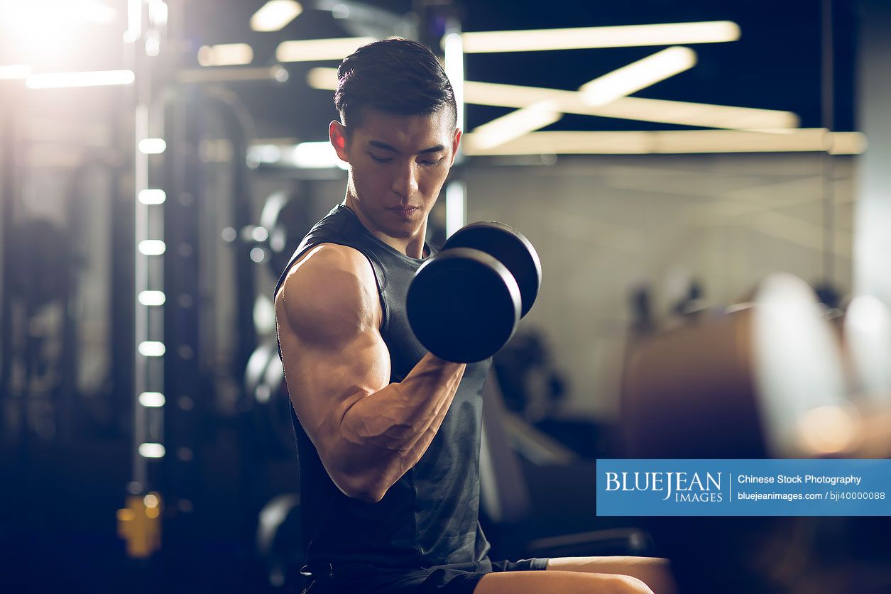 Young Chinese man working out with dumbbell at gym-High-res stock photo ...