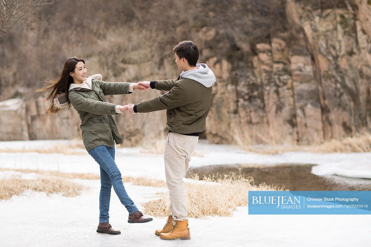 Happy young Chinese couple holding hands spinning-High-res stock photo for download