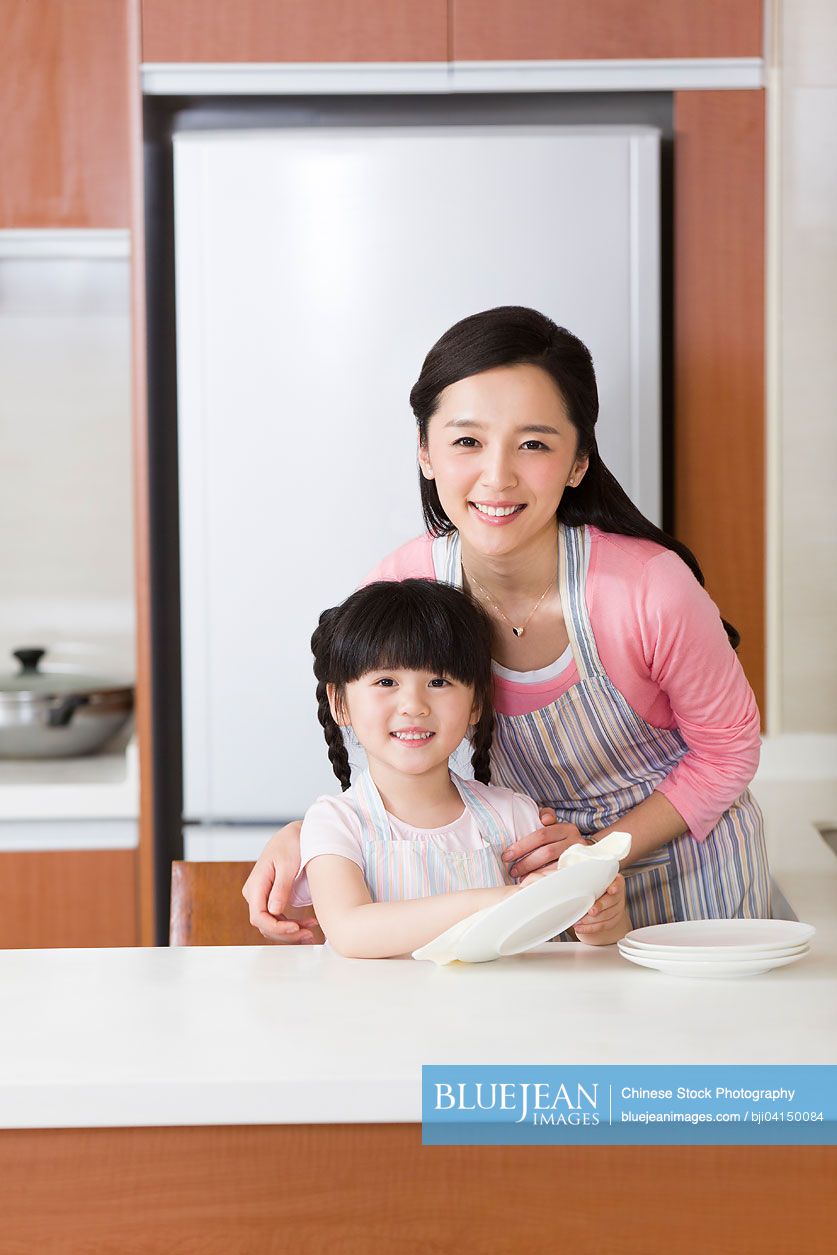 Cute Chinese girl drying plates for her mother-High-res stock photo for ...