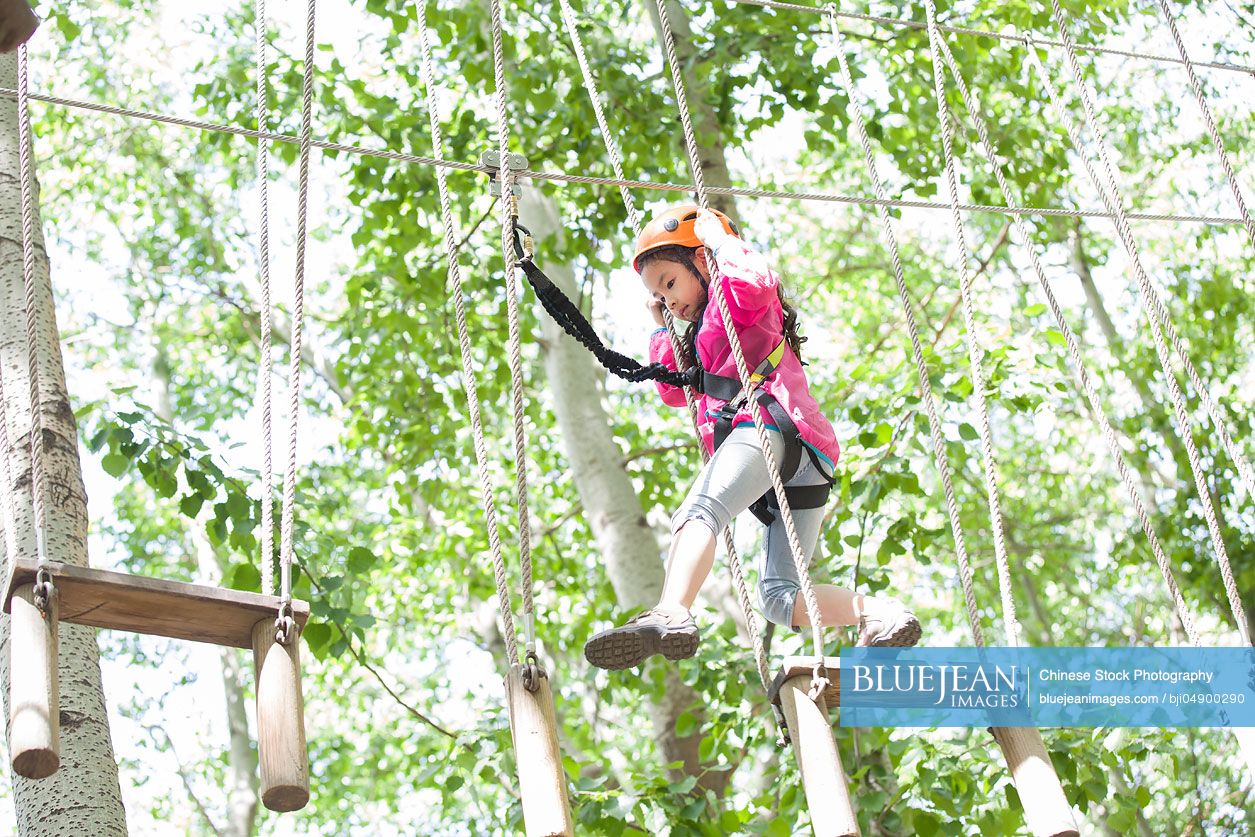 Little Chinese girl playing in tree top adventure park-High-res stock photo for download