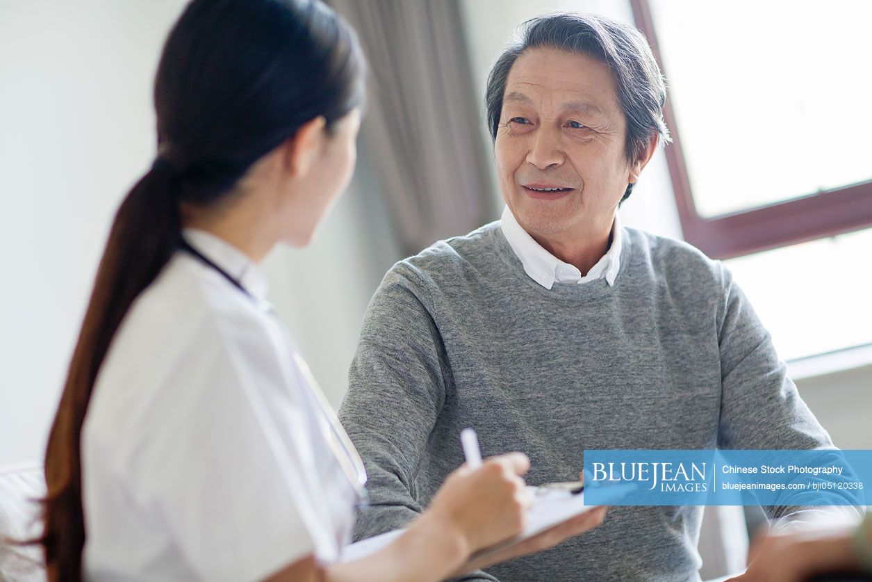 Chinese nursing assistant talking with senior man-High-res stock photo ...