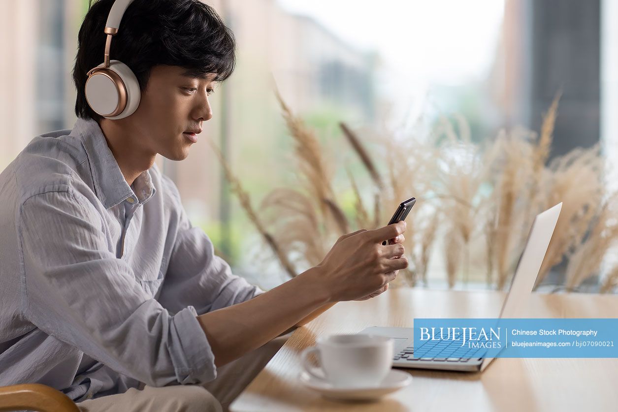 Young Chinese man using smartphone in café-High-res stock photo for ...