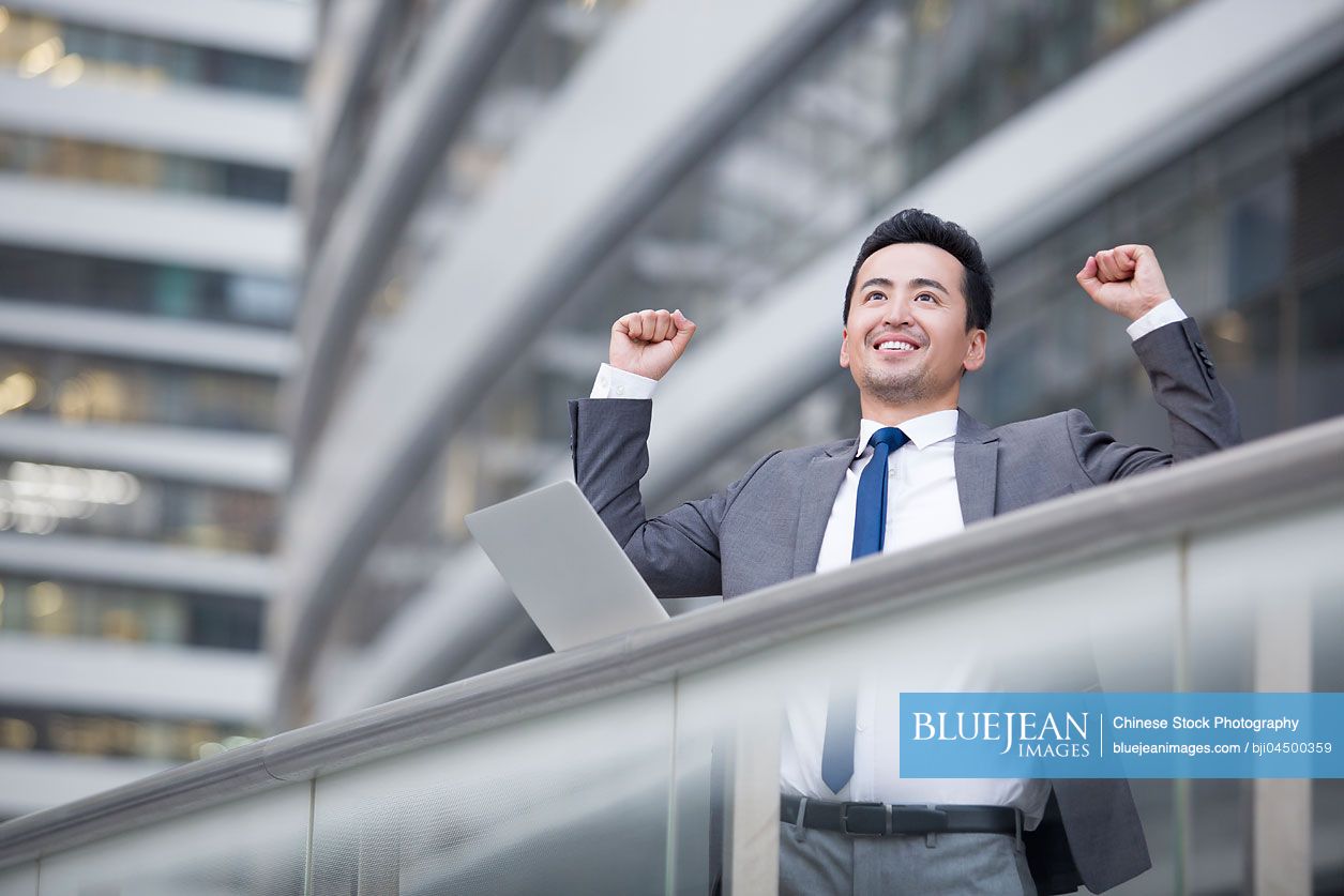 Chinese businessman using laptop outdoors-High-res stock photo for download