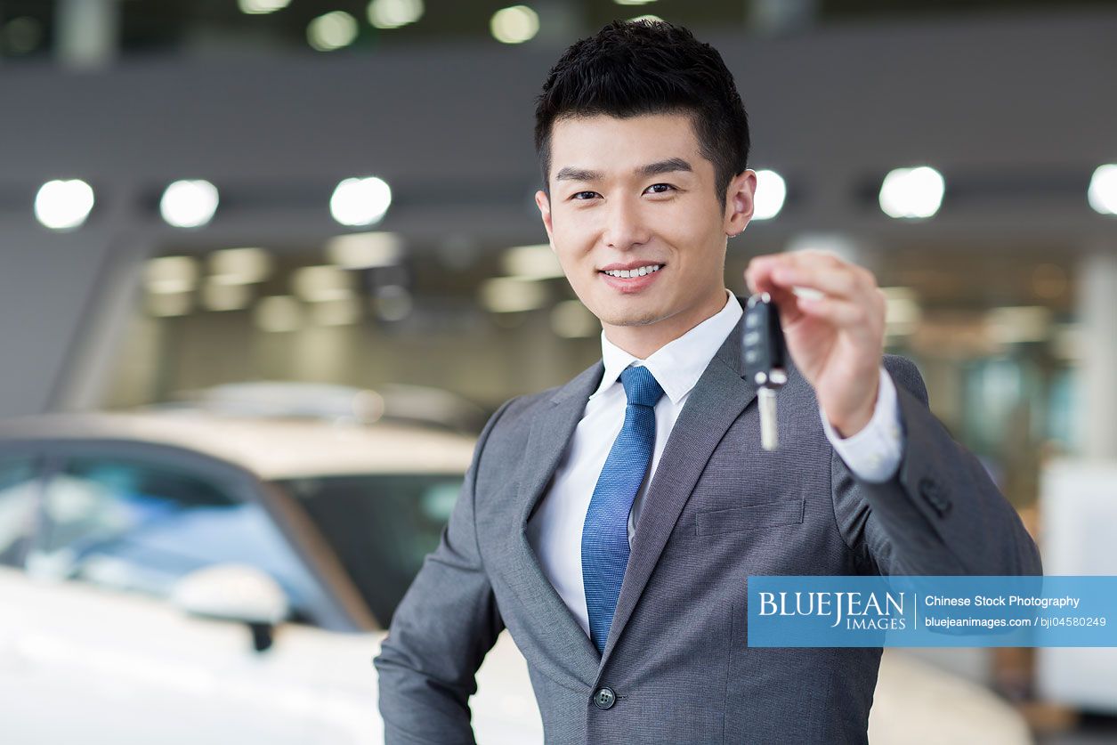 Confident Chinese salesman standing with new cars in showroom-High-res ...