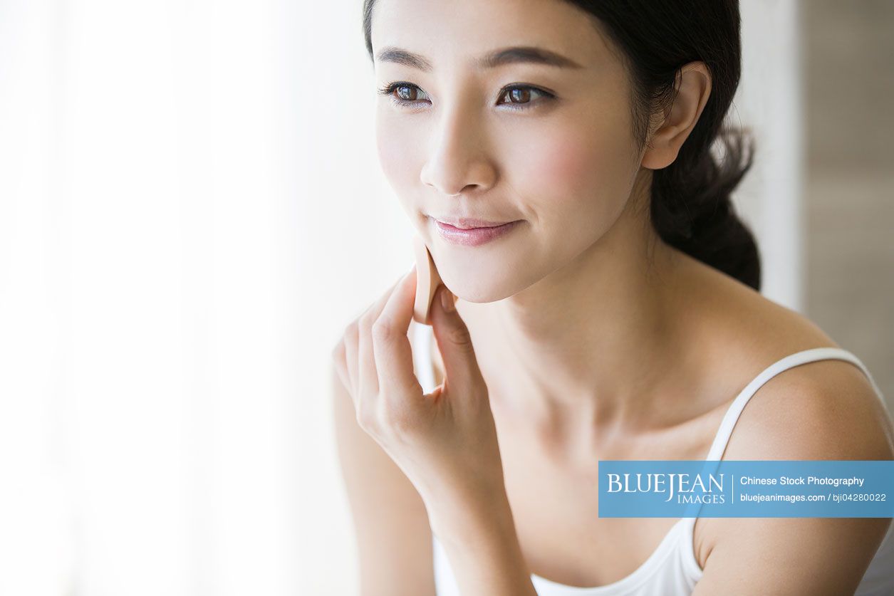 Young Chinese woman applying facial powder-High-res stock photo for ...