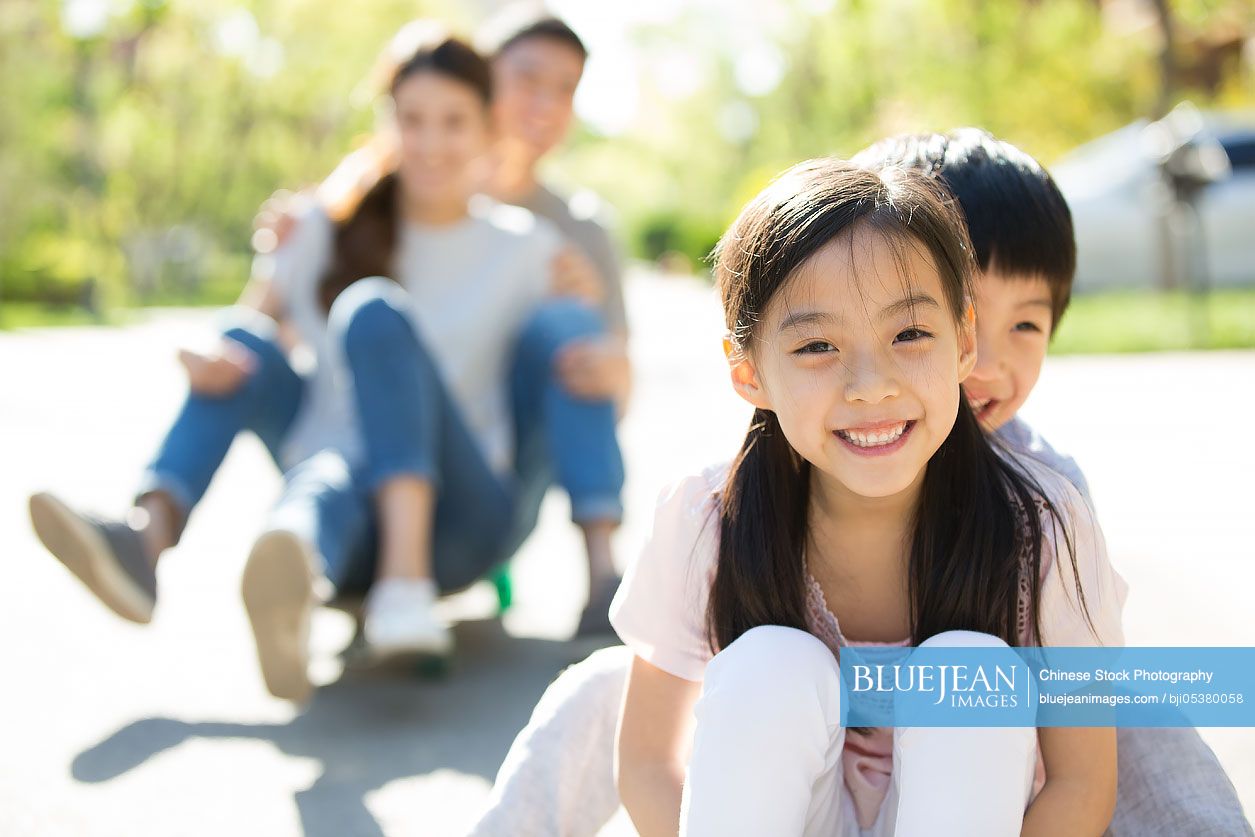 Happy young Chinese family playing with skateboards-High-res stock photo for download