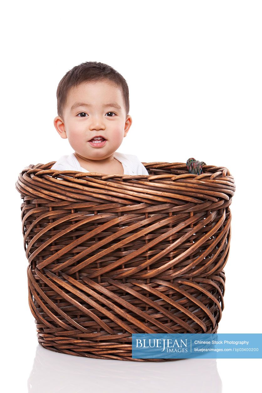 Happy Chinese baby boy in bamboo basket-High-res stock photo for download