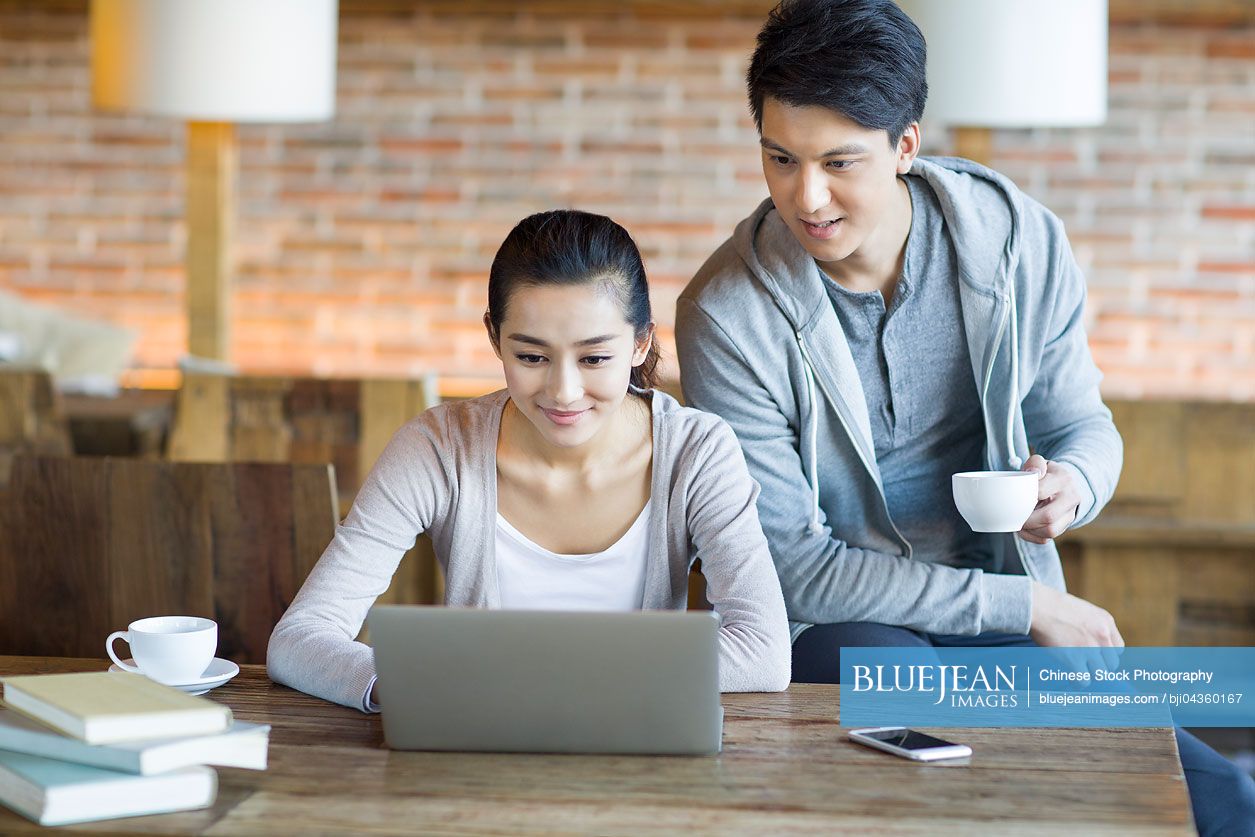 Young Chinese couple using laptop in cafe-High-res stock photo for download