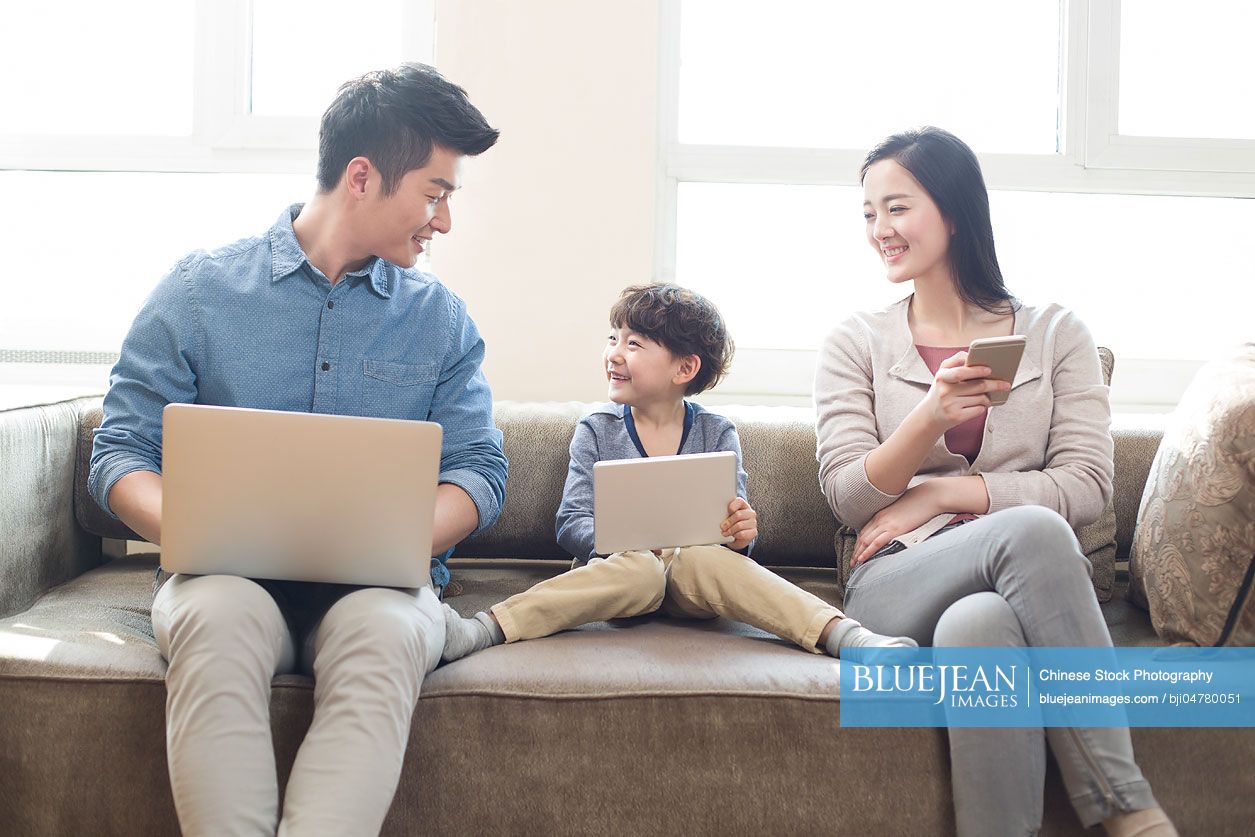Happy young Chinese family using laptop and digital tablet-High-res ...