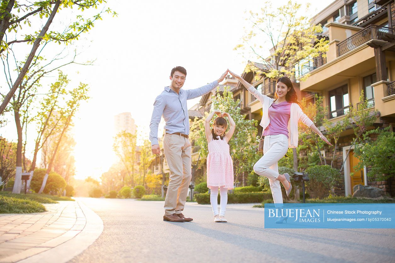 Happy young Chinese family standing in front of their new house-High ...