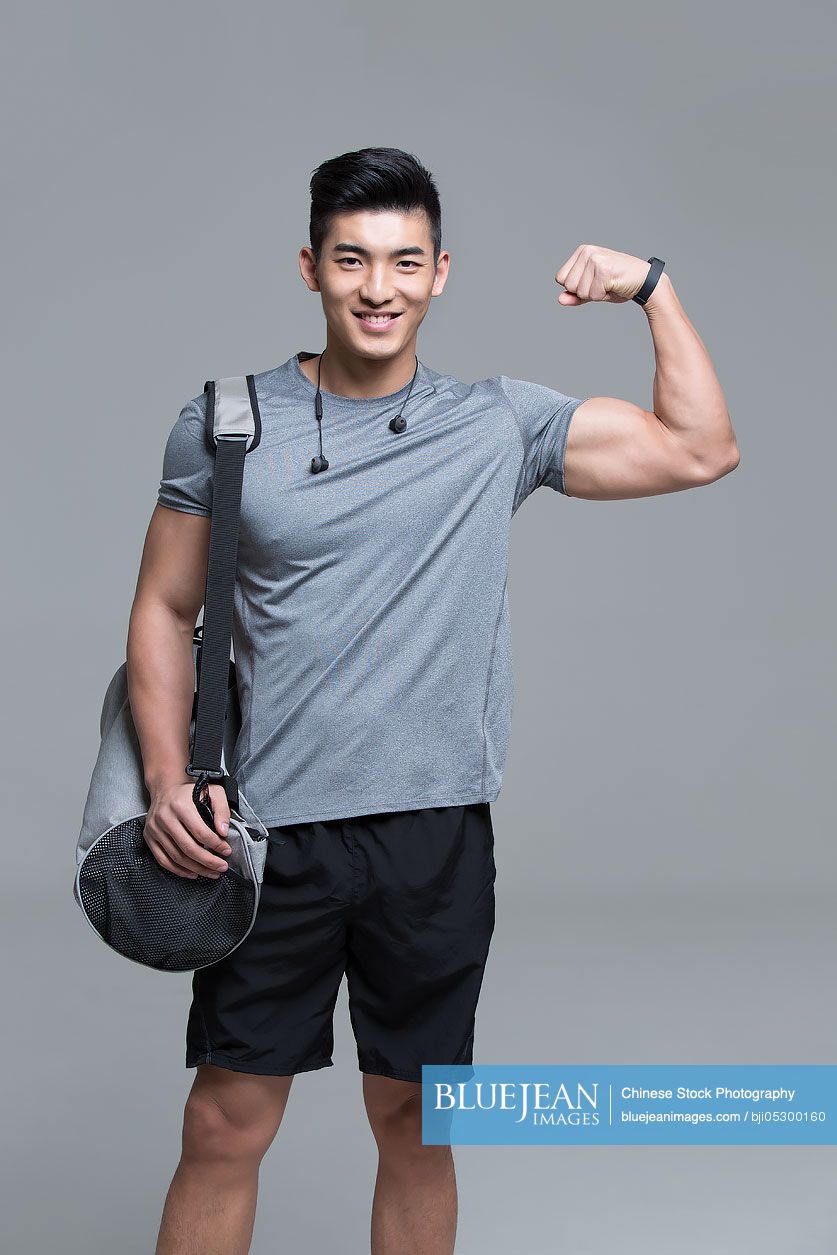 Cheerful young Chinese male athlete flexing muscles-High-res stock photo for download