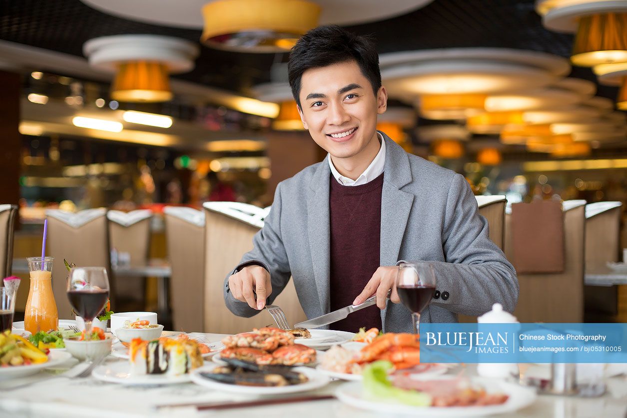 Cheerful young Chinese man having buffet dinner-High-res stock photo ...