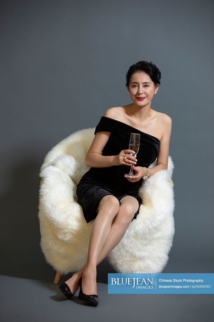 Beautiful mature Chinese woman drinking champagne-High-res stock photo ...
