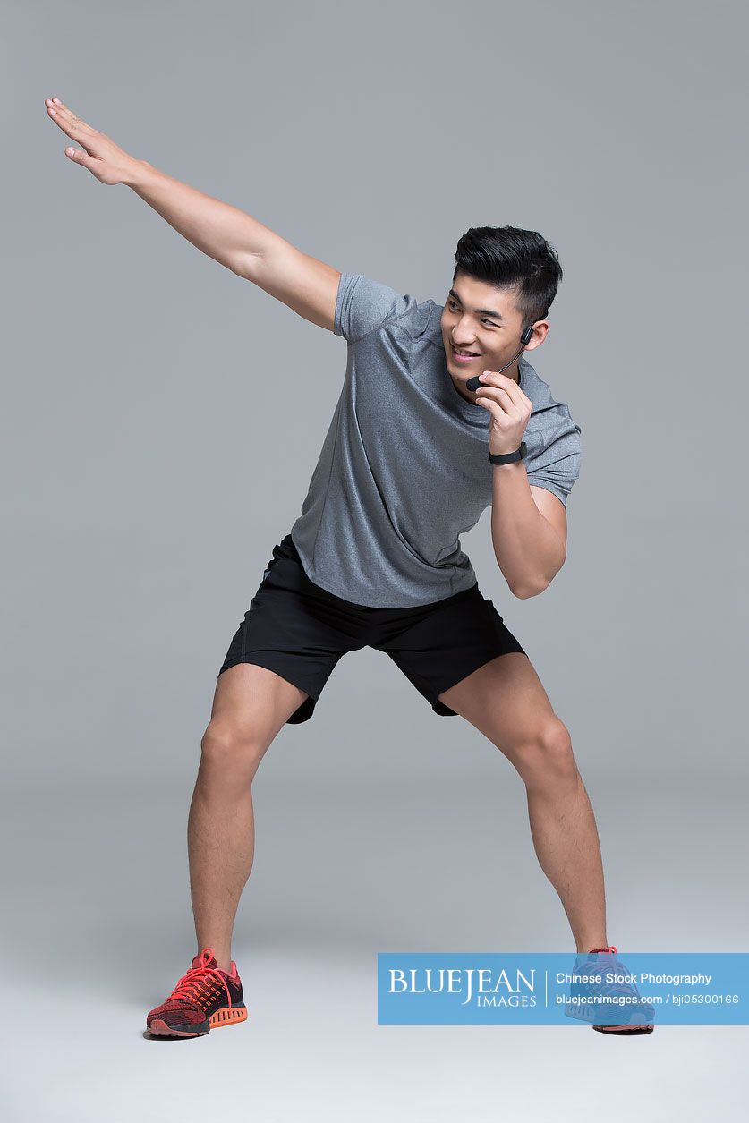 Cheerful young Chinese male trainer with headset teaching at gym-High-res stock photo for download