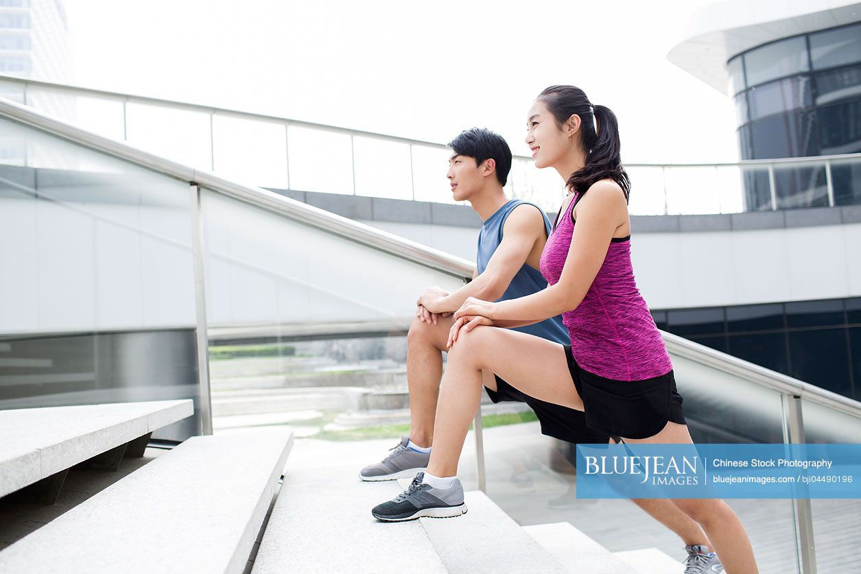 Young Chinese couple stretching legs on stairs-High-res stock photo for download