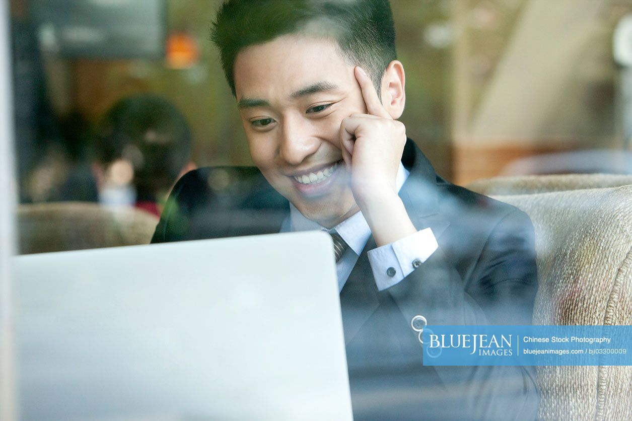 Happy Chinese businessman using laptop in cafe-High-res stock photo for download