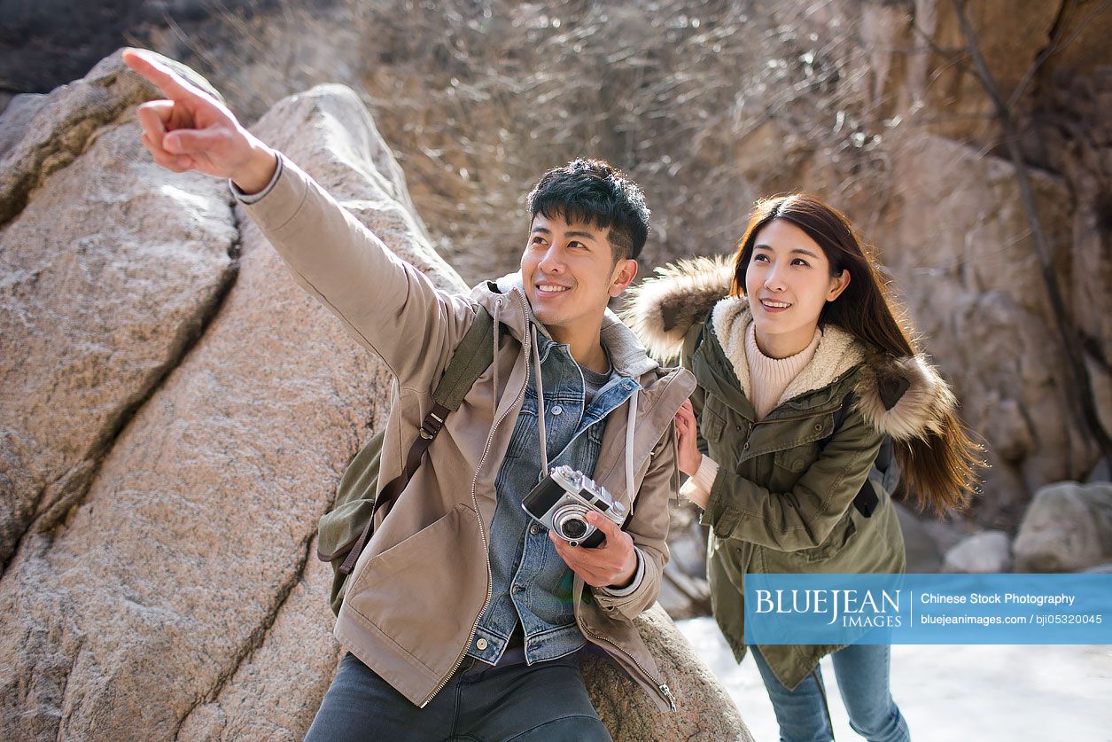 Happy young Chinese couple with camera enjoying winter outing-High-res stock photo for download