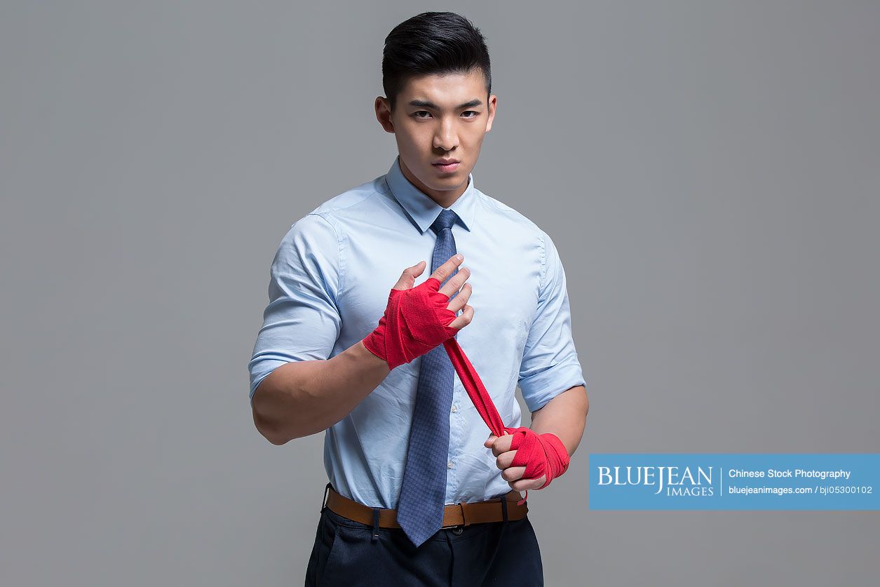 Young Chinese businessman wrapping hands for boxing-High-res stock photo for download