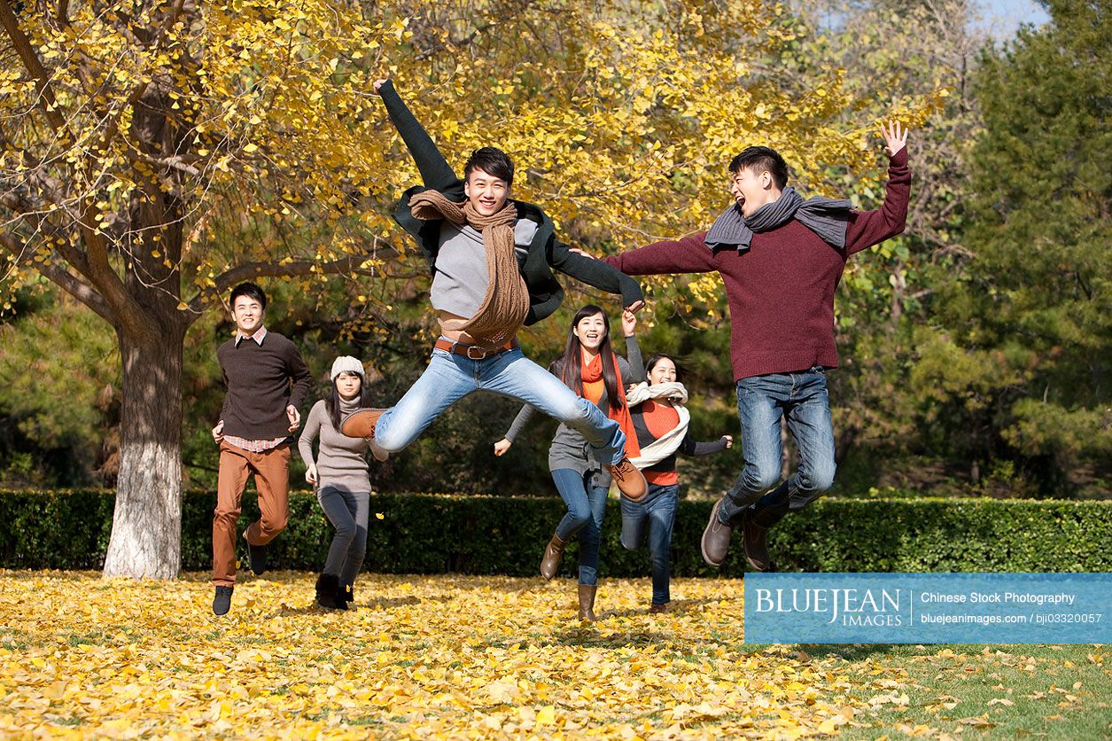 Excited young Chinese adults jumping on the lawn in autumn-High-res ...
