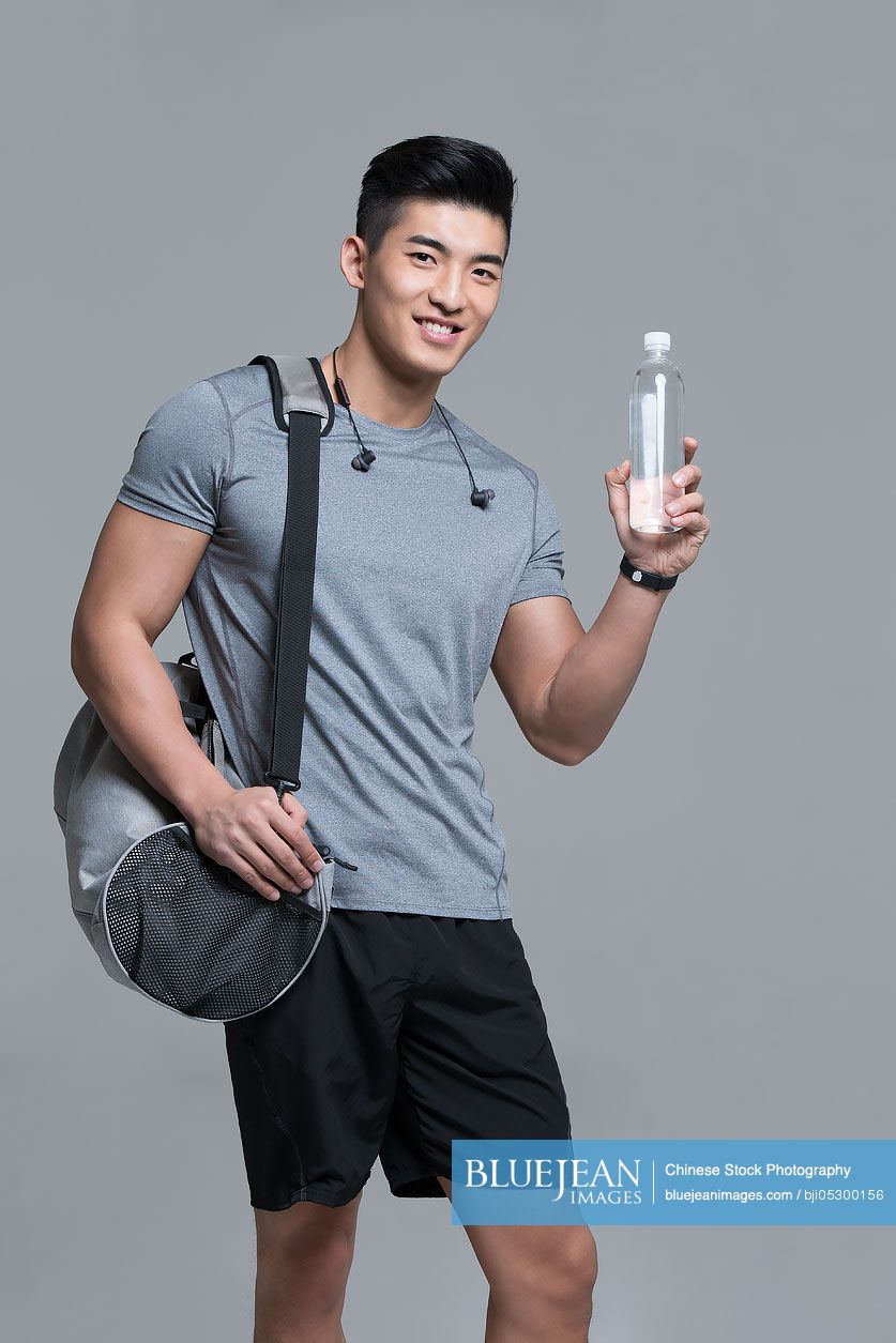 Cheerful young Chinese male athlete holding a bottle of water-High-res stock photo for download
