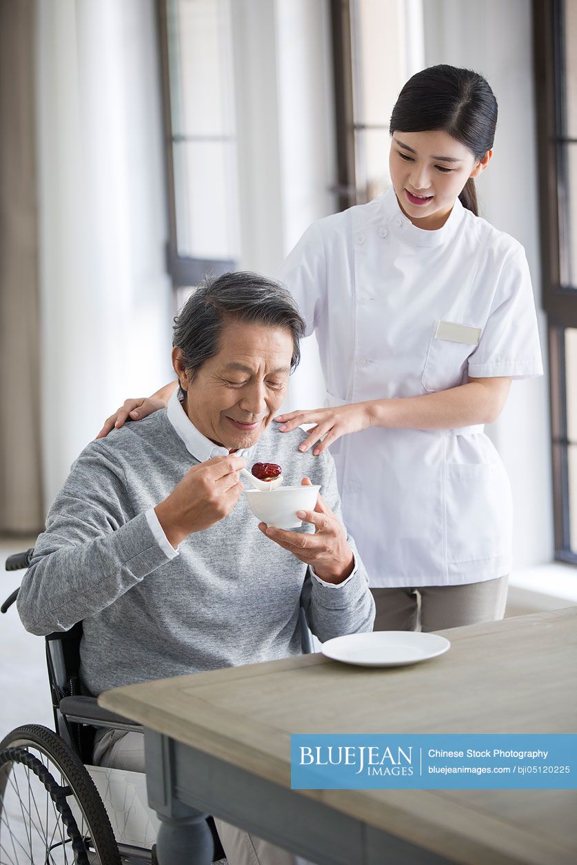 Chinese nursing assistant taking care of senior man in wheel chair-High ...