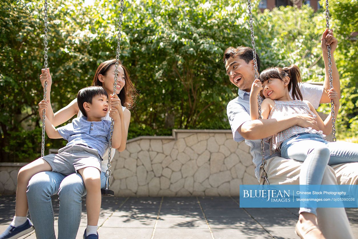 Happy young Chinese family playing on swings-High-res stock photo for download