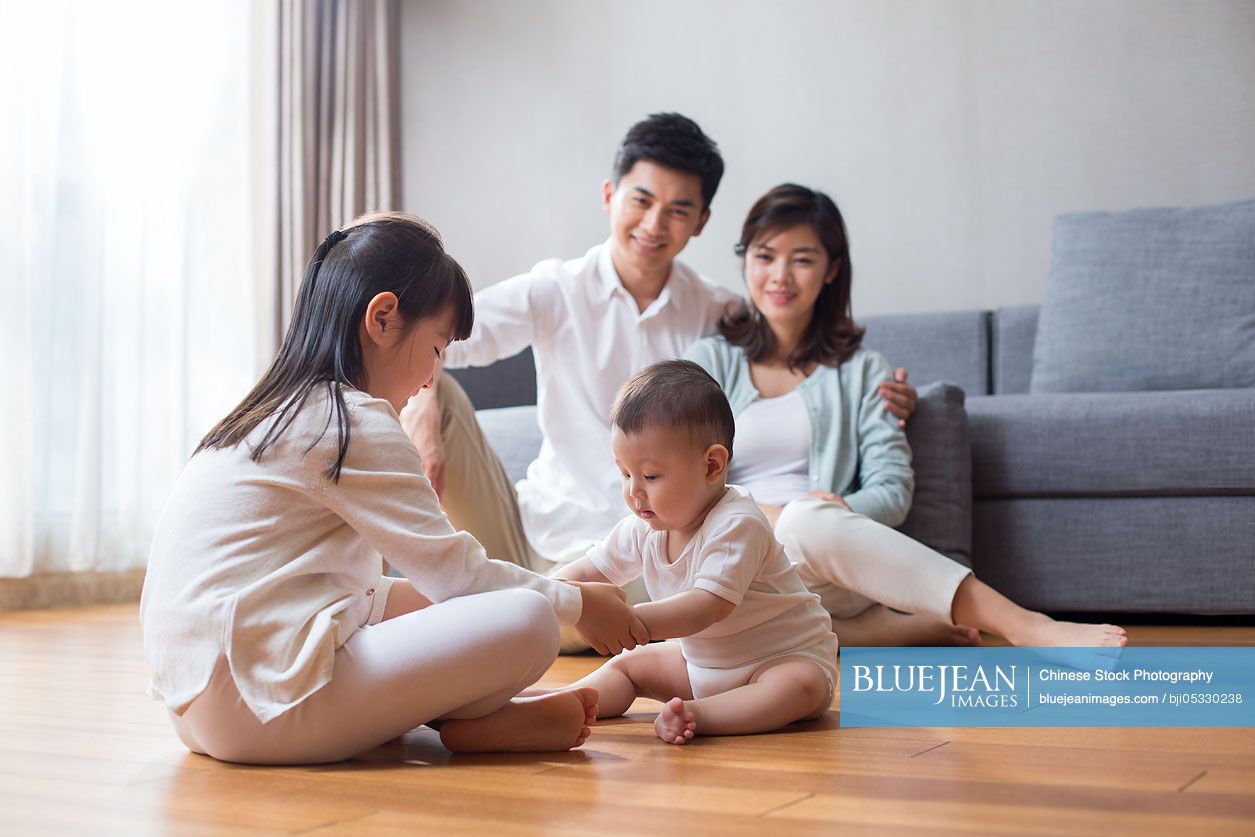 Happy young Chinese family sitting on wooden floor-High-res stock photo ...