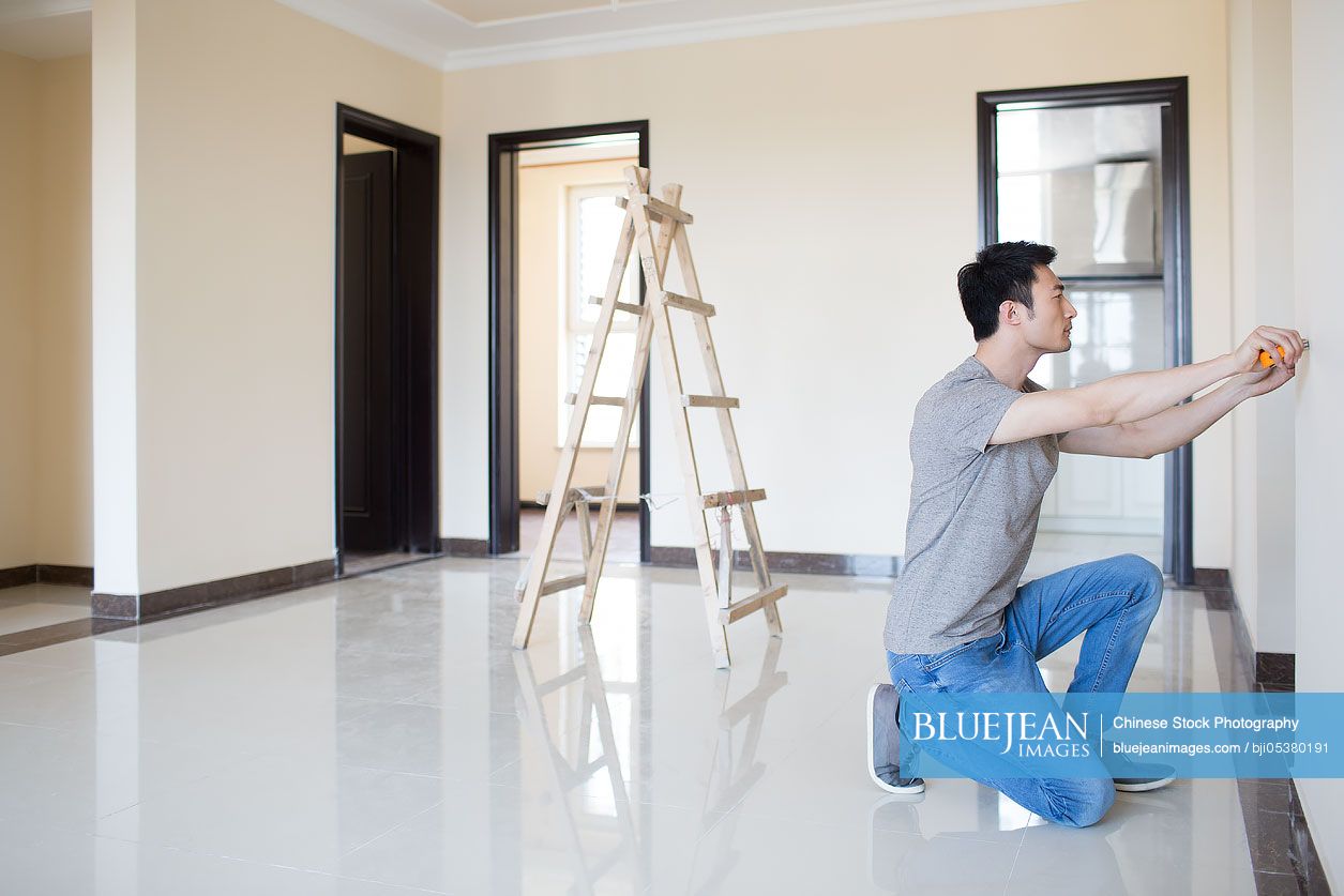 Young Chinese man measuring wall-High-res stock photo for download