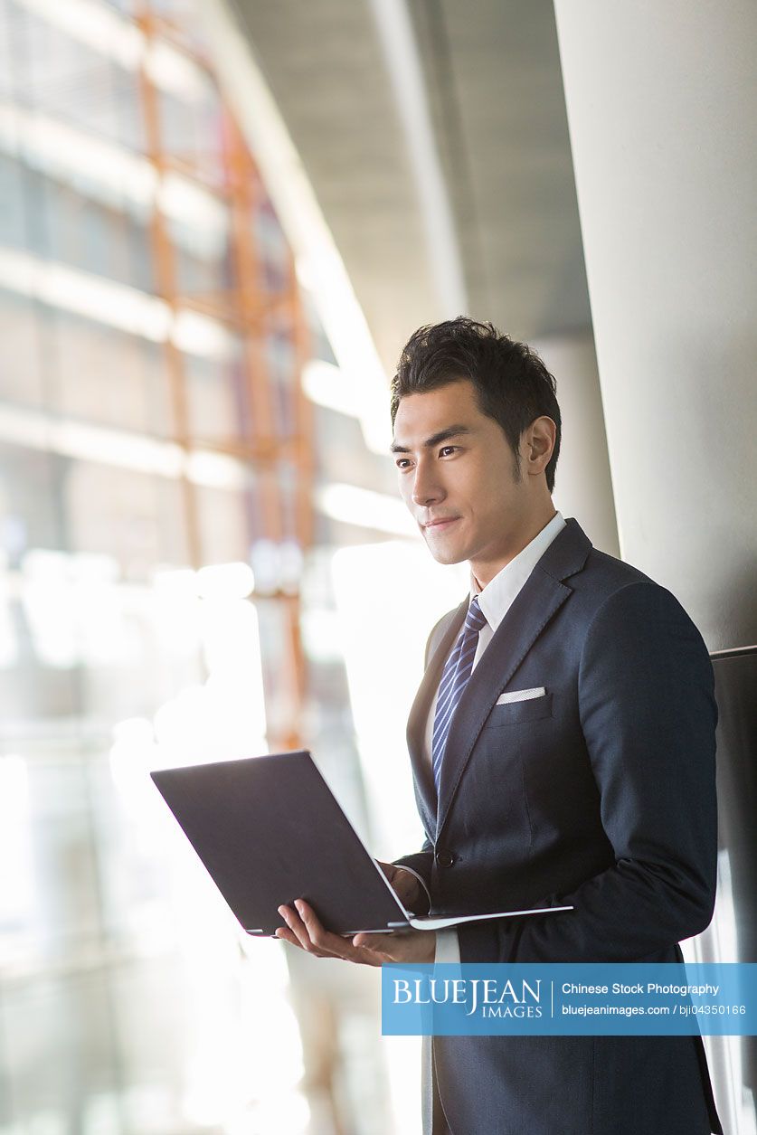 Young Chinese businessman using laptop in airport-High-res stock photo ...