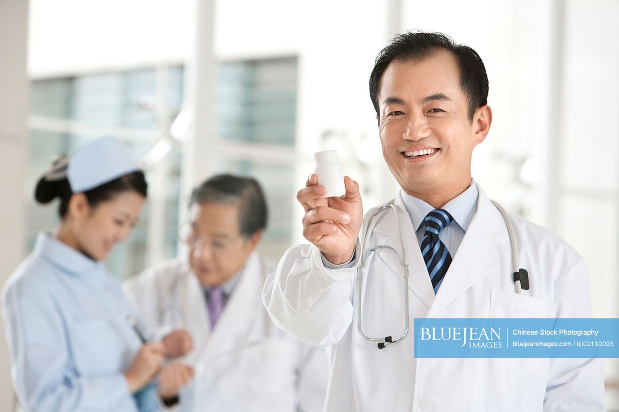 Chinese doctor offering prescription medicine with doctor and nurse in ...