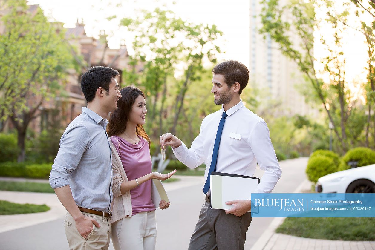 Happy young Chinese couple receiving house key from real estate agent-High-res stock photo for ...