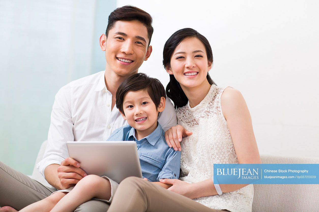 Cheerful young Chinese family with digital tablet in the living room ...
